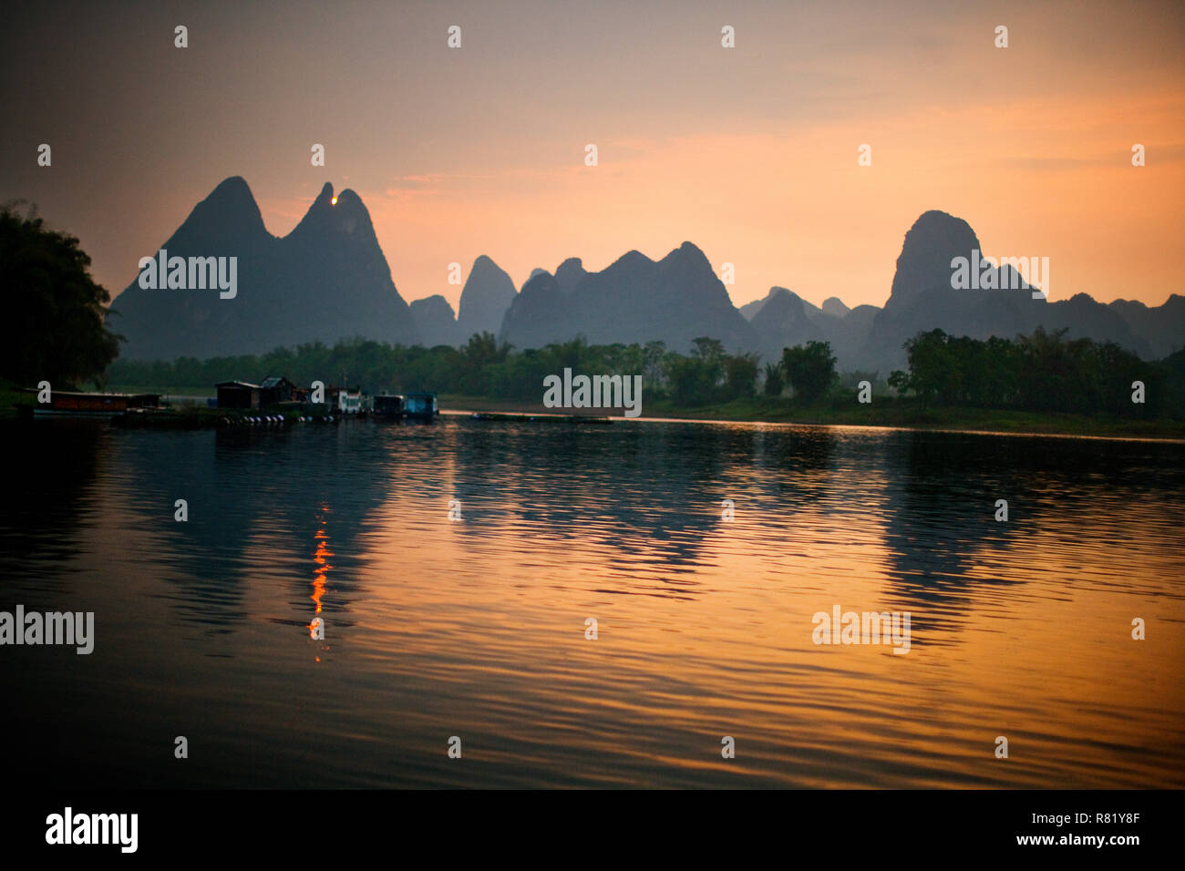 Sun setting behind mountains Stock Photo - Alamy