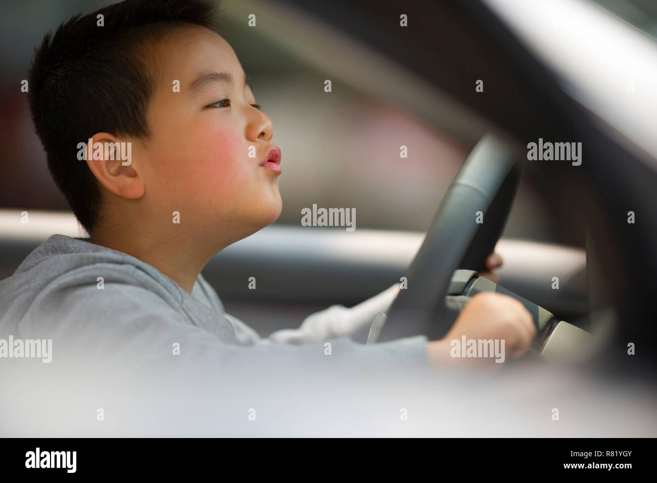 Young boy looking over the top of a steering wheel inside a car Stock ...