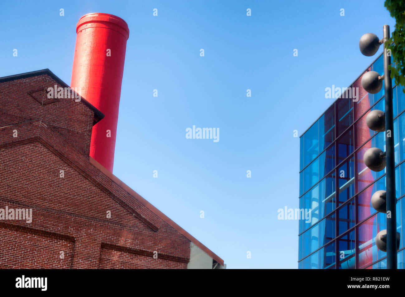 Abstract roof line that includes a red smoke stack with a blue sky ...