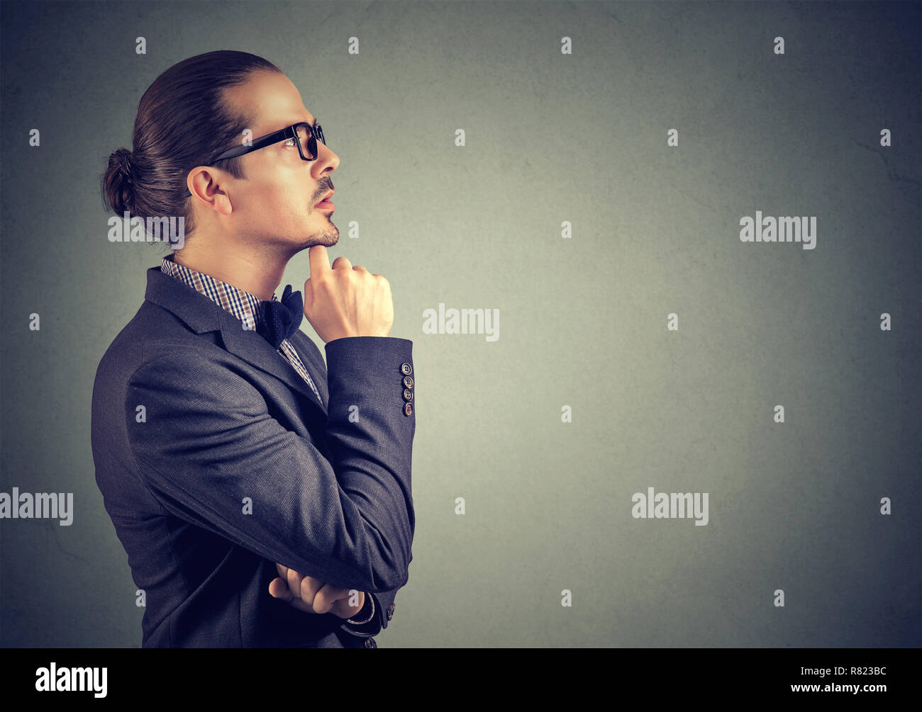 Adult man touching chin with finger and looking away in deep thoughts ...