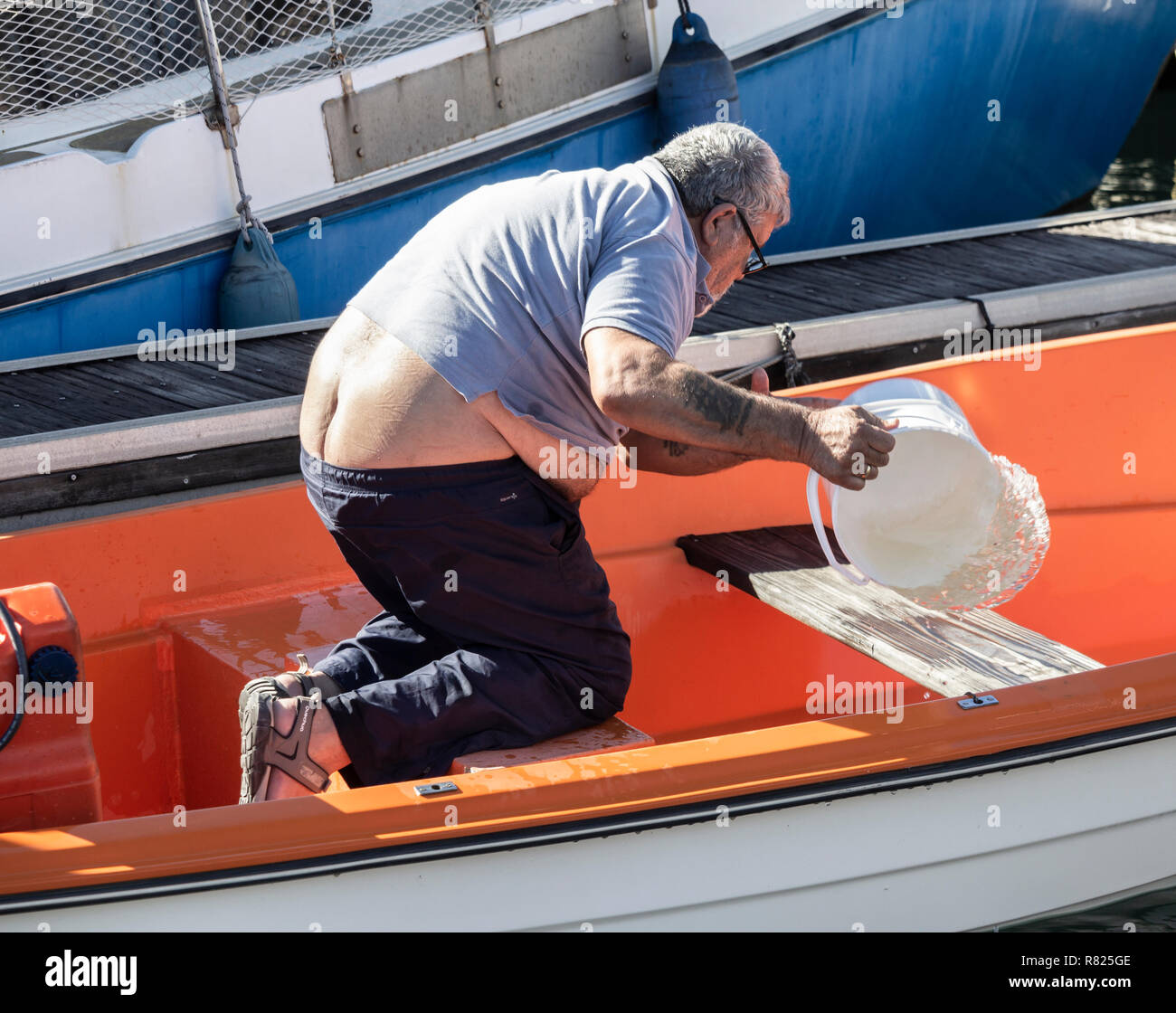 Man emptying water from boat showing Builder`s bum Stock Photo - Alamy