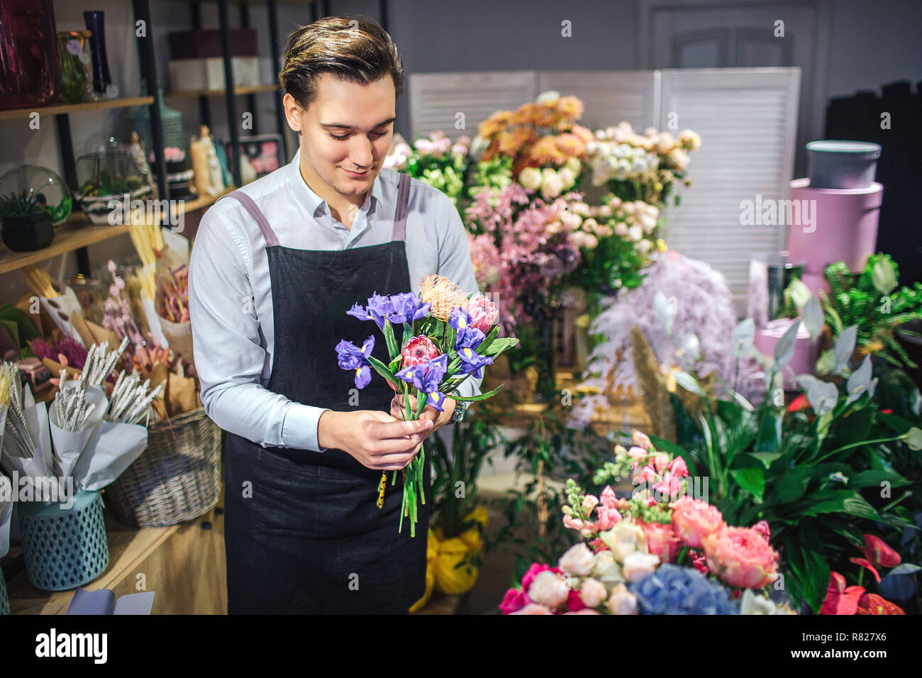 Cheerful young male florist hold colorful bouquet in hands. He look at ...