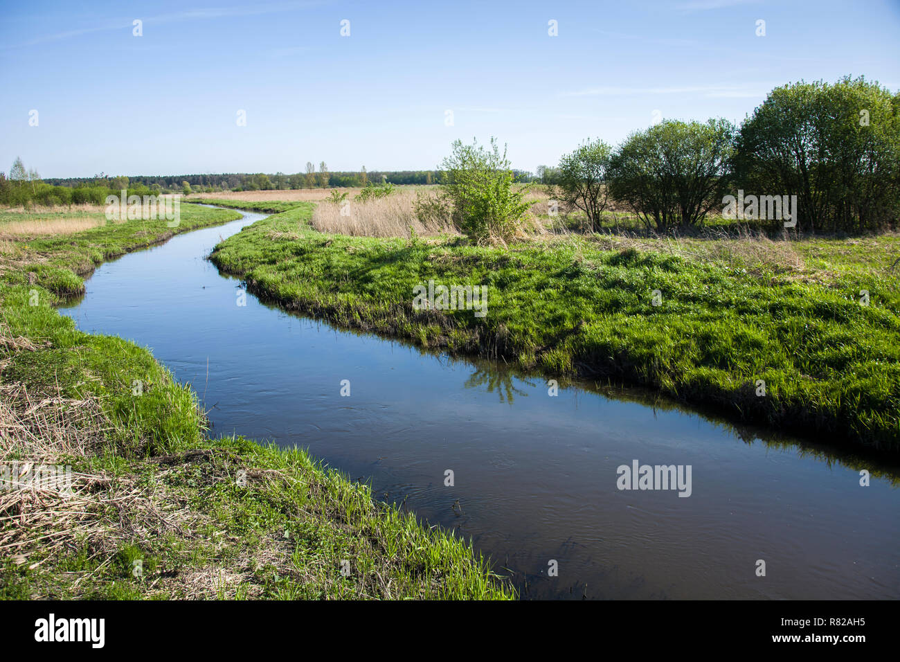 Small calm river with green shores and blue sky Stock Photo - Alamy