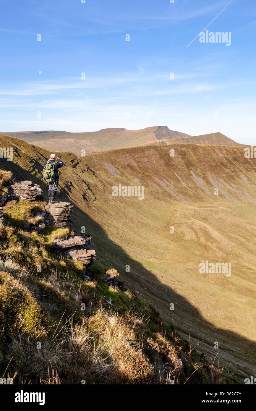 A hiker standing on a outcrop of rock, takes in the view of the highest ...