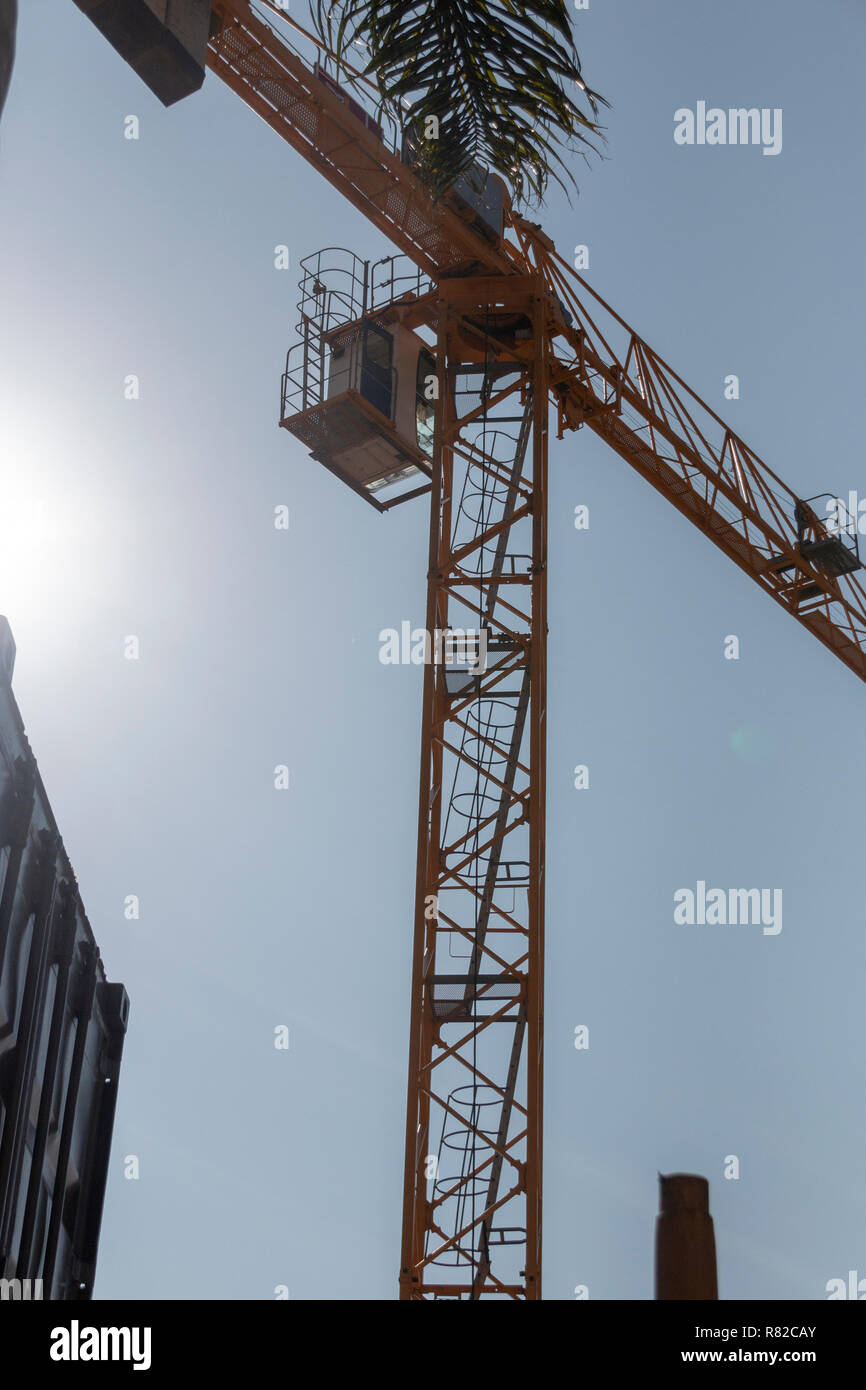 A close up view from the ground of a yellow crane working on a ...