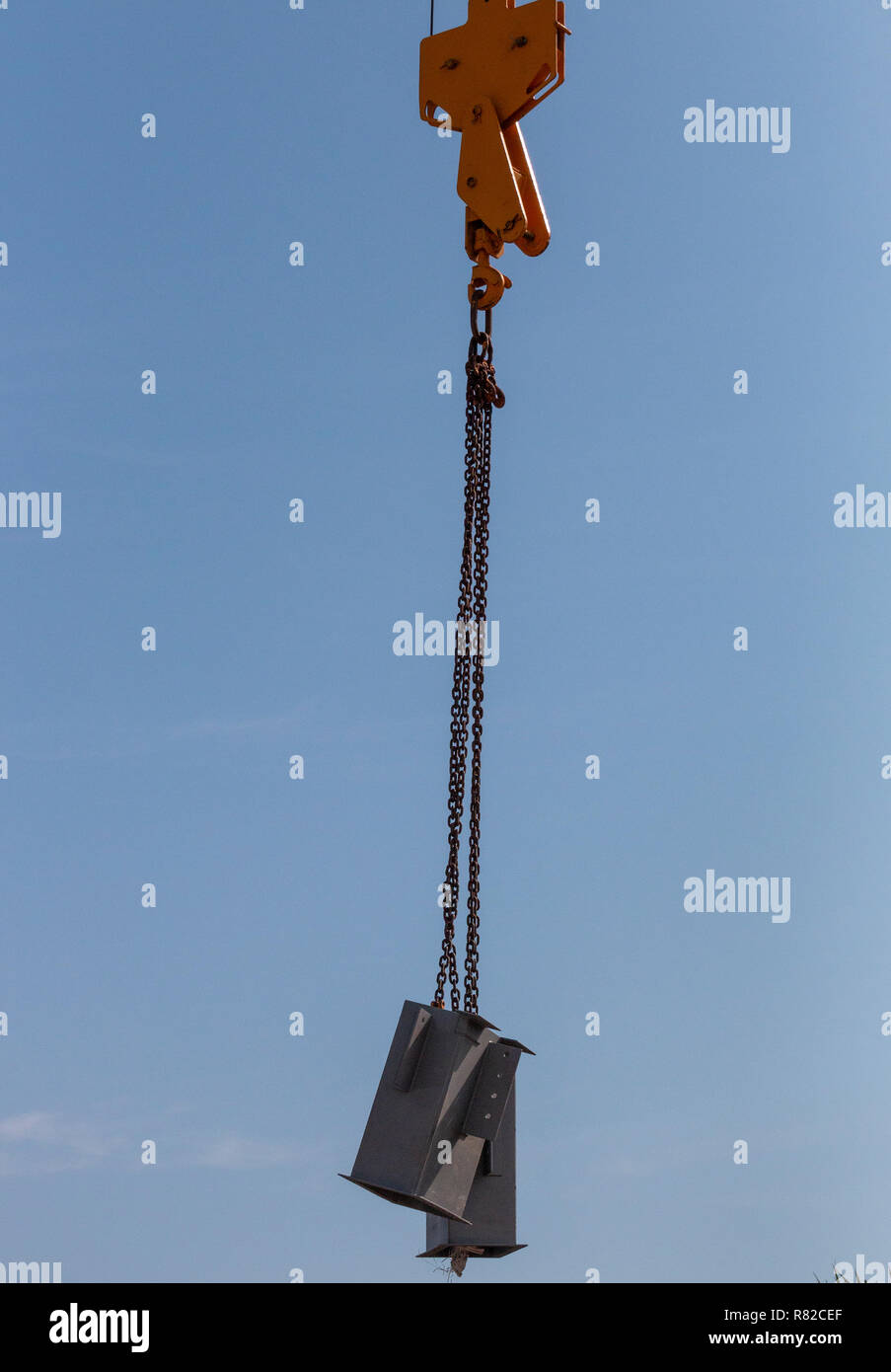 A Close up view of the arm of a yellow crane liftting up a metal stands ...