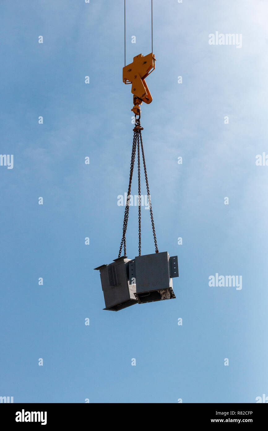 A Close up view of the arm of a yellow crane liftting up a metal stands ...
