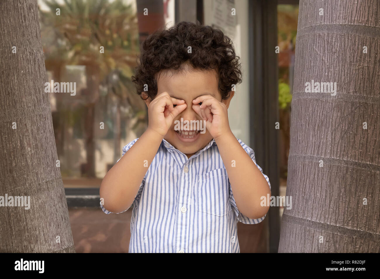 A little boy pretends to use his hands as binoculars looking at me. Out ...