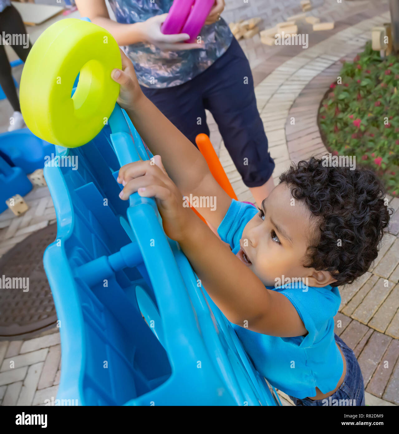 A determined little boy wants to insert the green doughnut-shaped ring ...