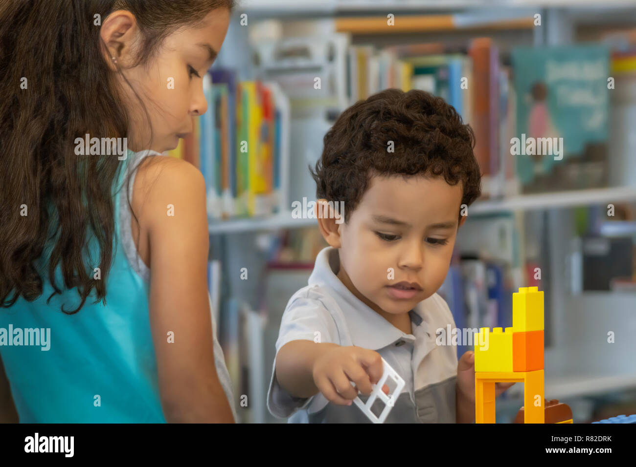 Big sister and Littel brother playing at the library. Young siblings ...