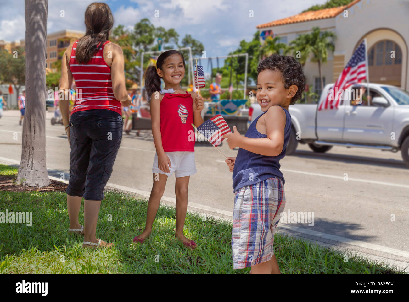 4th of July parade passes by as the kids enjoy waving the American flag ...