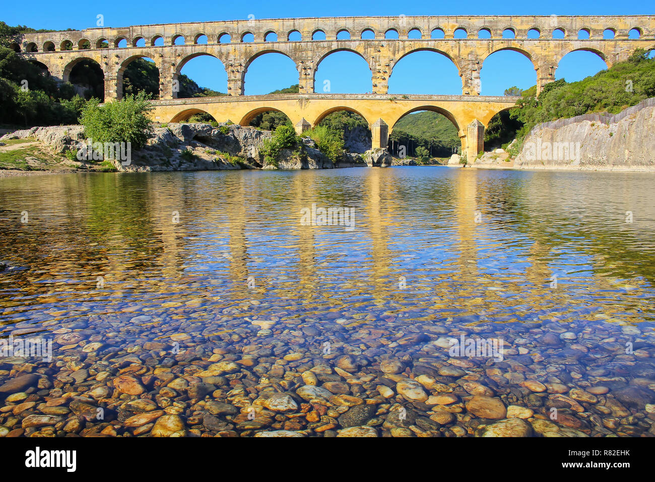 Aqueduct Pont du Gard reflected in Gardon River, southern France. It is ...