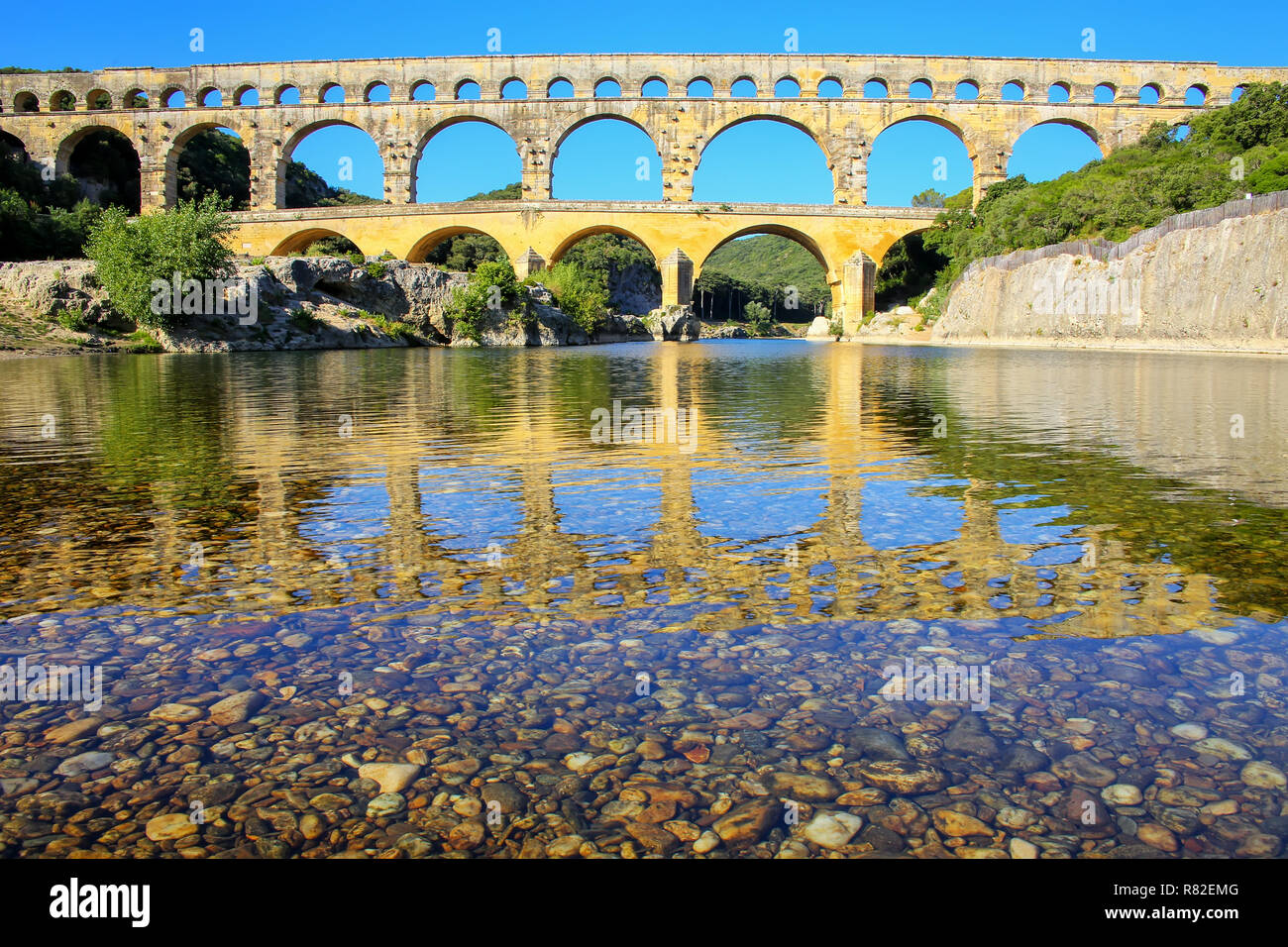 Aqueduct Pont du Gard reflected in Gardon River, southern France. It is ...