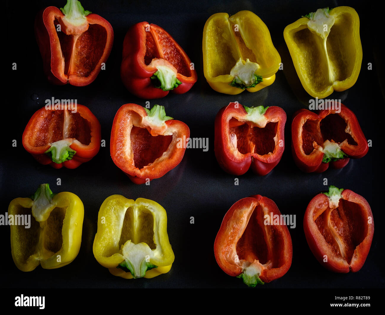 Red and yellow bell peppers cut in half on black background Stock Photo ...