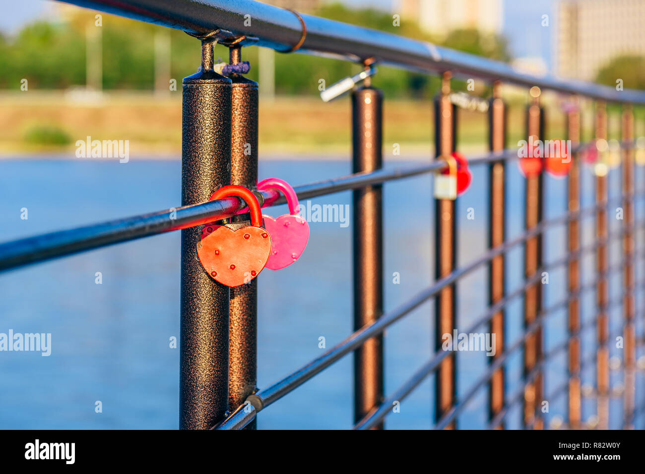 Colorful metal locks hanging on black railings in the sunrise light ...