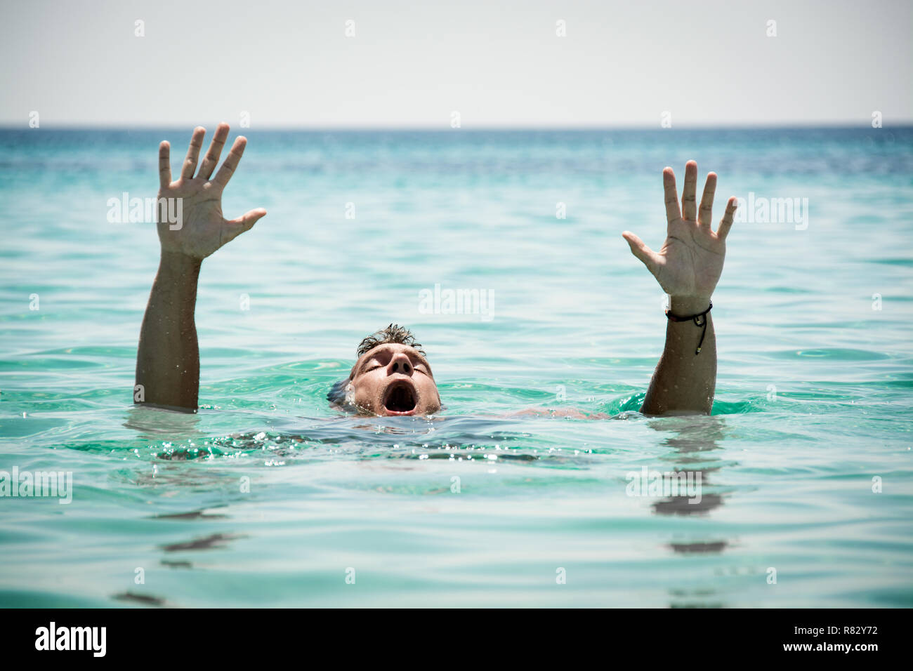 Drowning man in sea asking for help with raised arms Stock Photo - Alamy