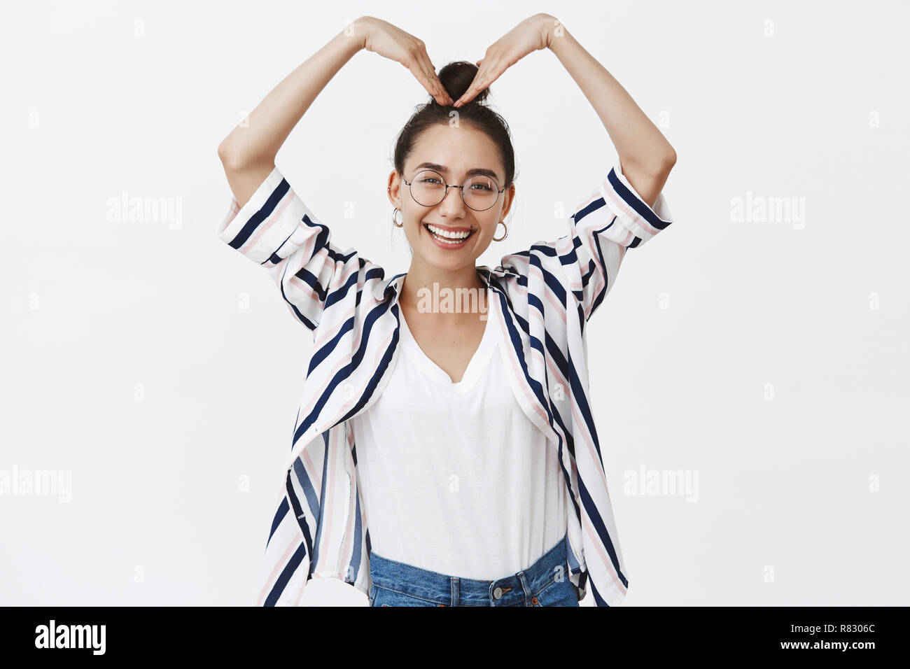 Love you. Indoor shot of happy and funny cute woman in glasses and bun ...