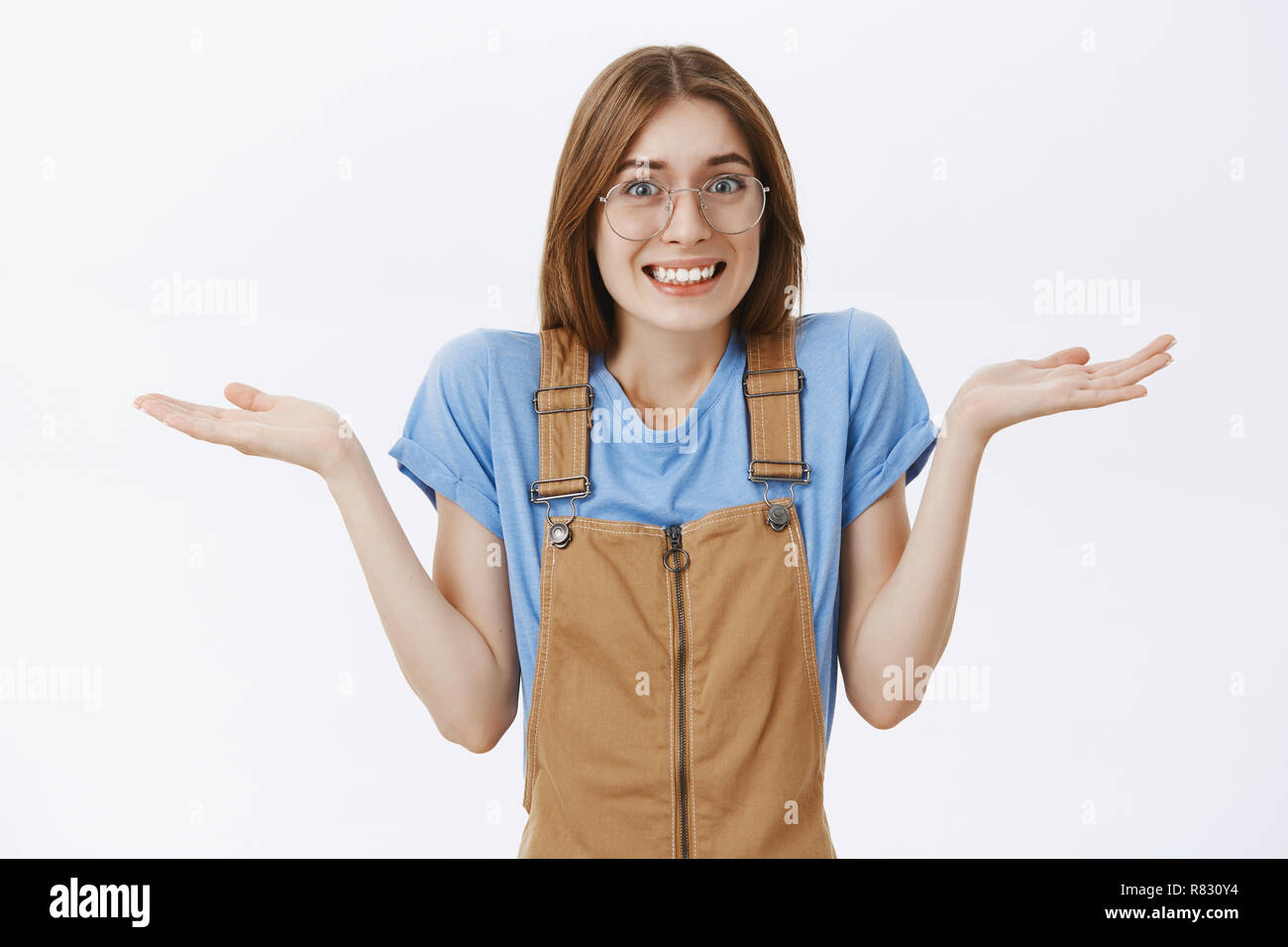 Waist-up shot of awkward cute charismatic young woman in brown overalls ...