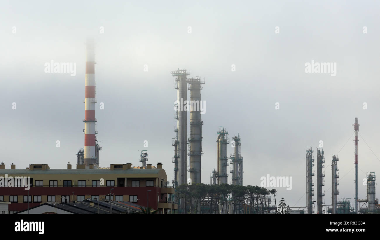 Part of a big oil refinery with the chimneys and towers in the fog ...