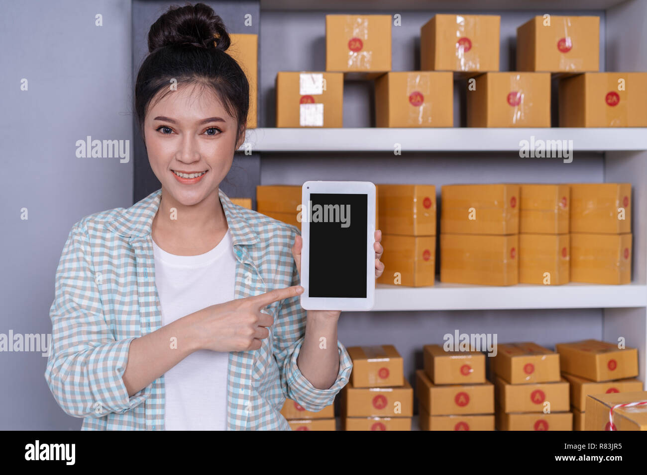 happy woman with her digital tablet and courier parcel box at home ...
