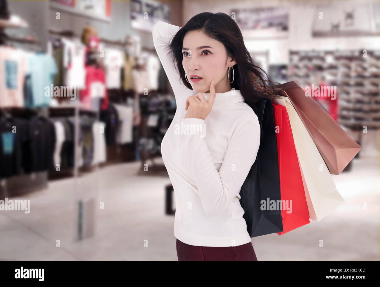 young woman thinking and holding shopping bag at mall Stock Photo - Alamy
