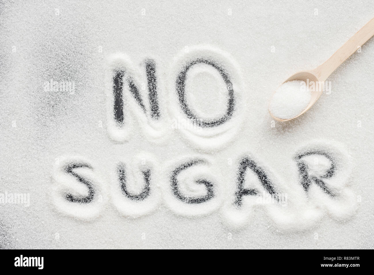 "no sugar" lettering written on granulated sugar with wooden spoon ...