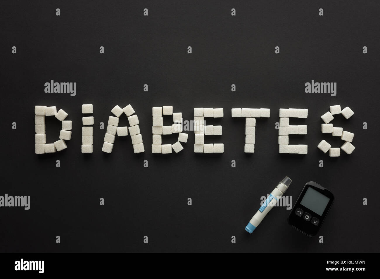 "diabetes" lettering made of sugar cubes with glucometer on black ...