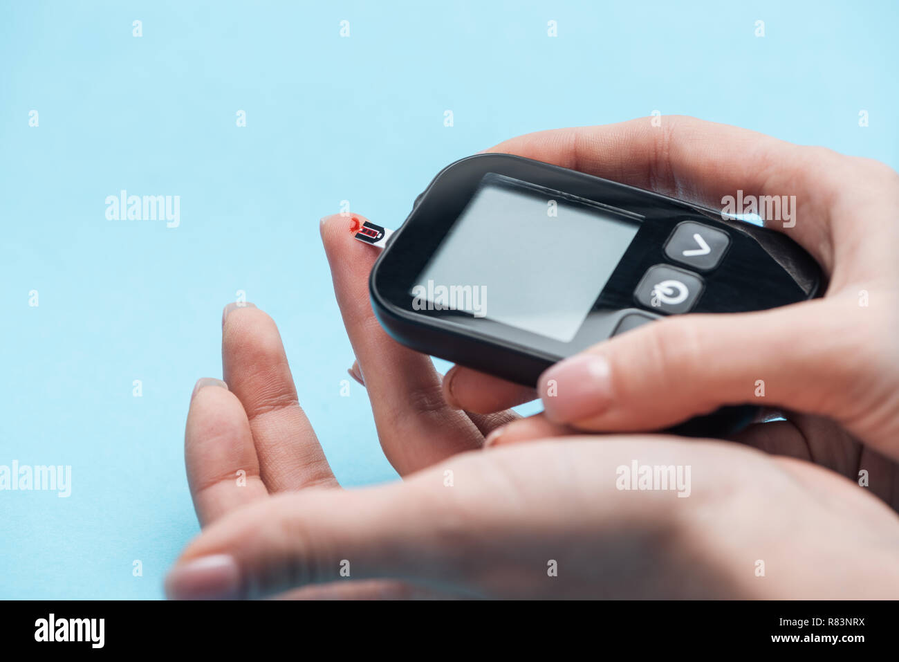 cropped view of female hands testing glucose level with glucometer on ...