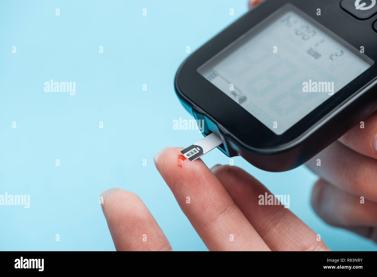 partial view of female fingers testing glucose level with glucometer ...