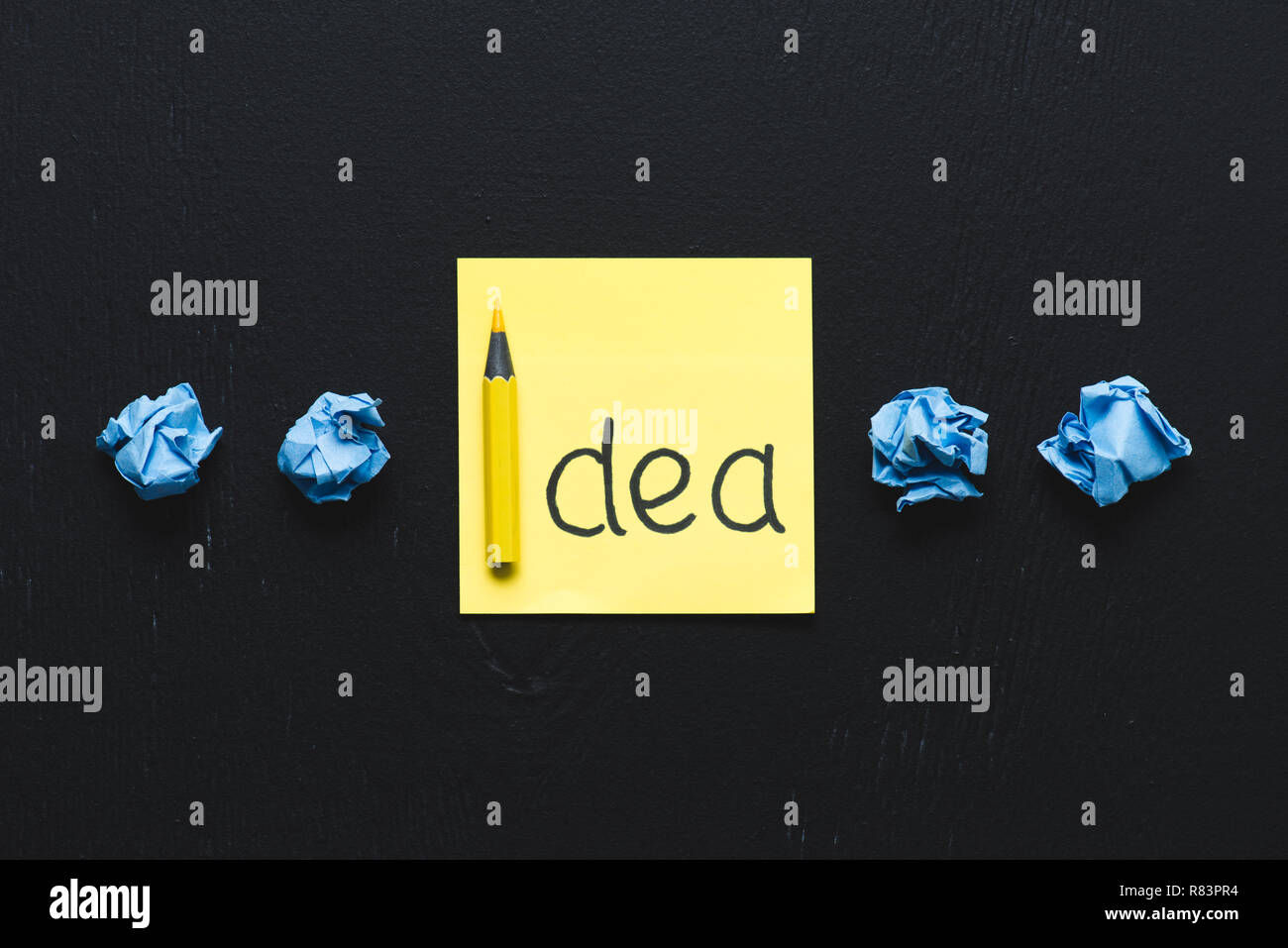 'idea' word written on sticky note and blue crumpled paper balls on ...