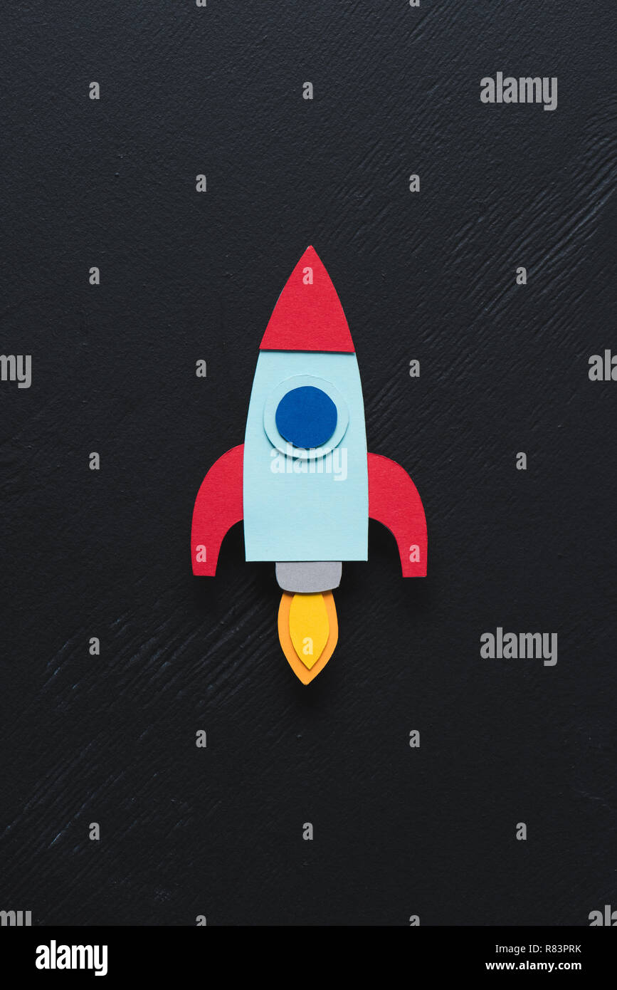 top view of flying paper rocket on black background, setting goals ...