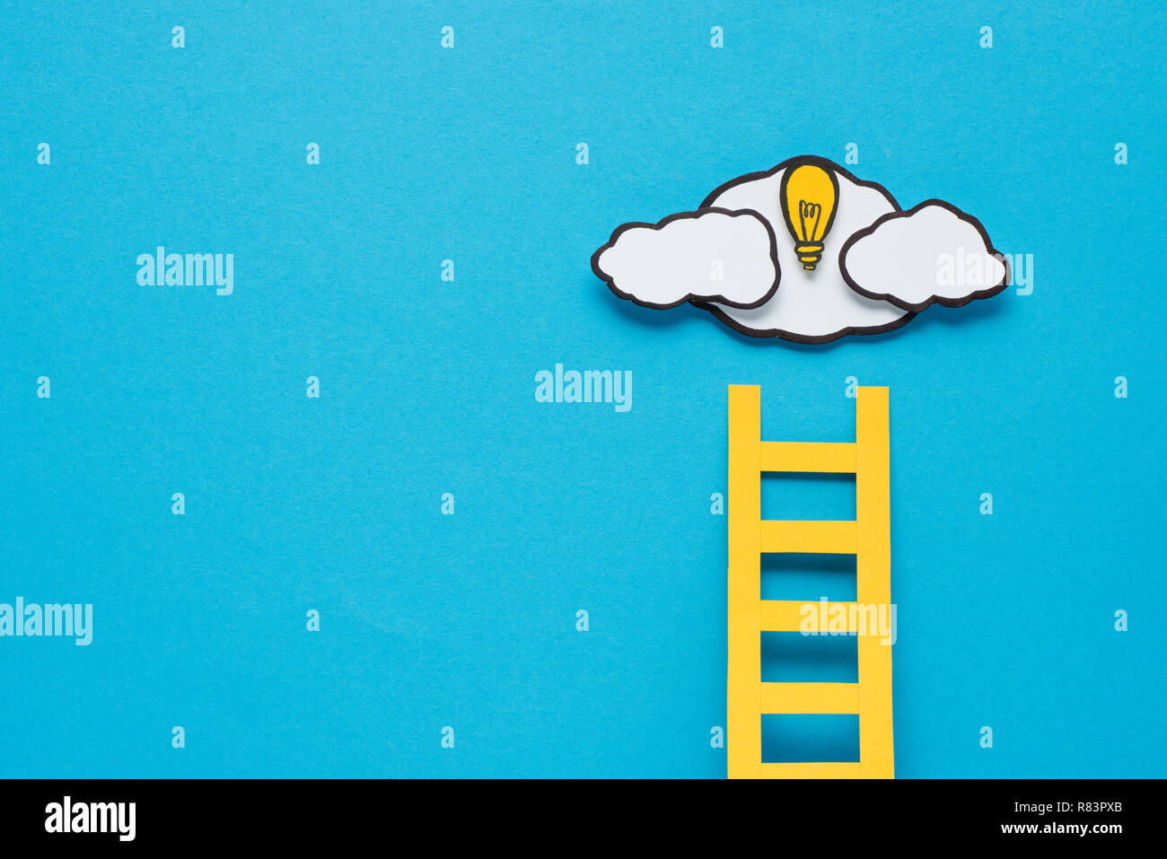 cardboard ladder, light bulb and clouds with copy space on blue ...