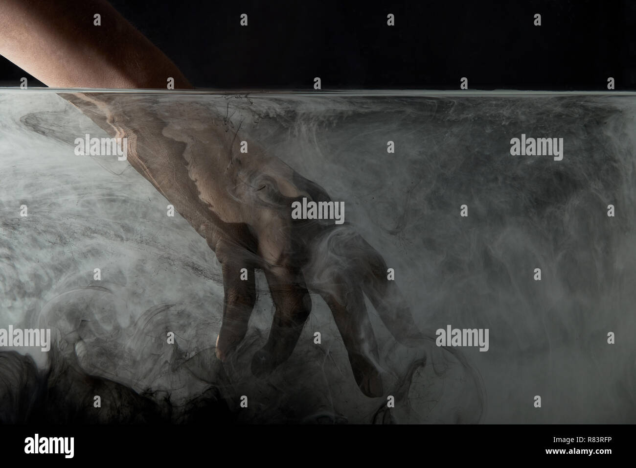 cropped view of person putting hand into water with dark paint Stock ...