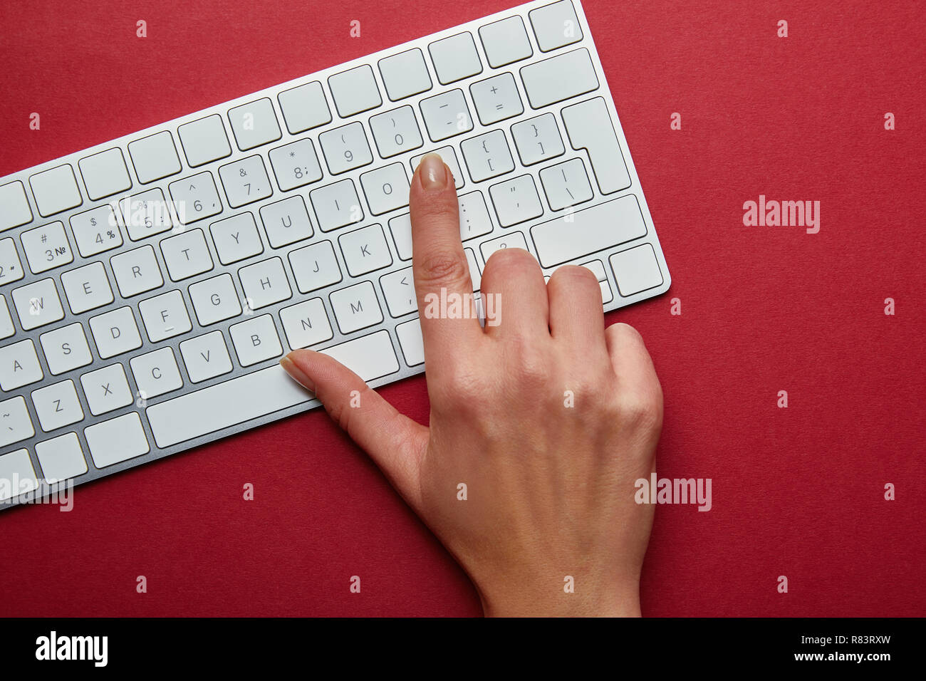 Top view of woman pushing button on white computer keyboard on red ...