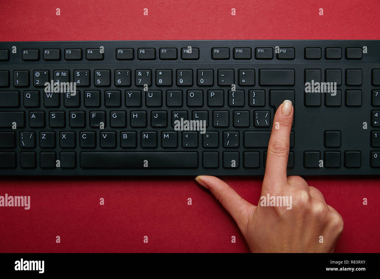 Top view of woman pushing button on black computer keyboard on red ...