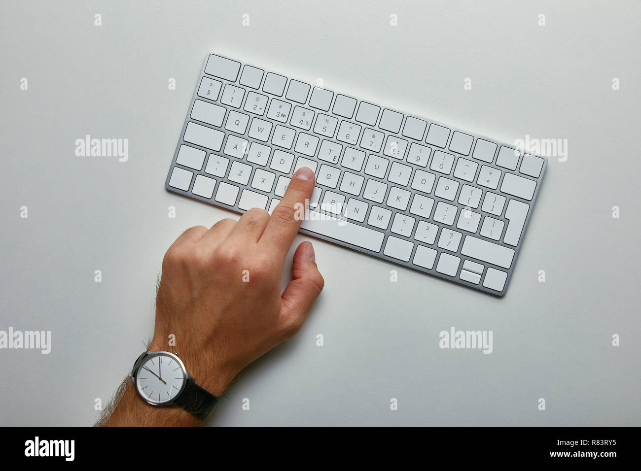 Cropped view of man pushing button on computer keyboard on grey ...