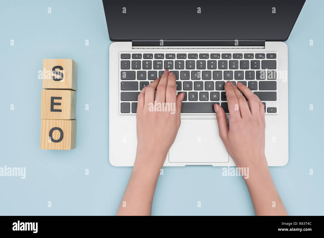 Top view of female seo manager typing on laptop keyboard on light blue ...