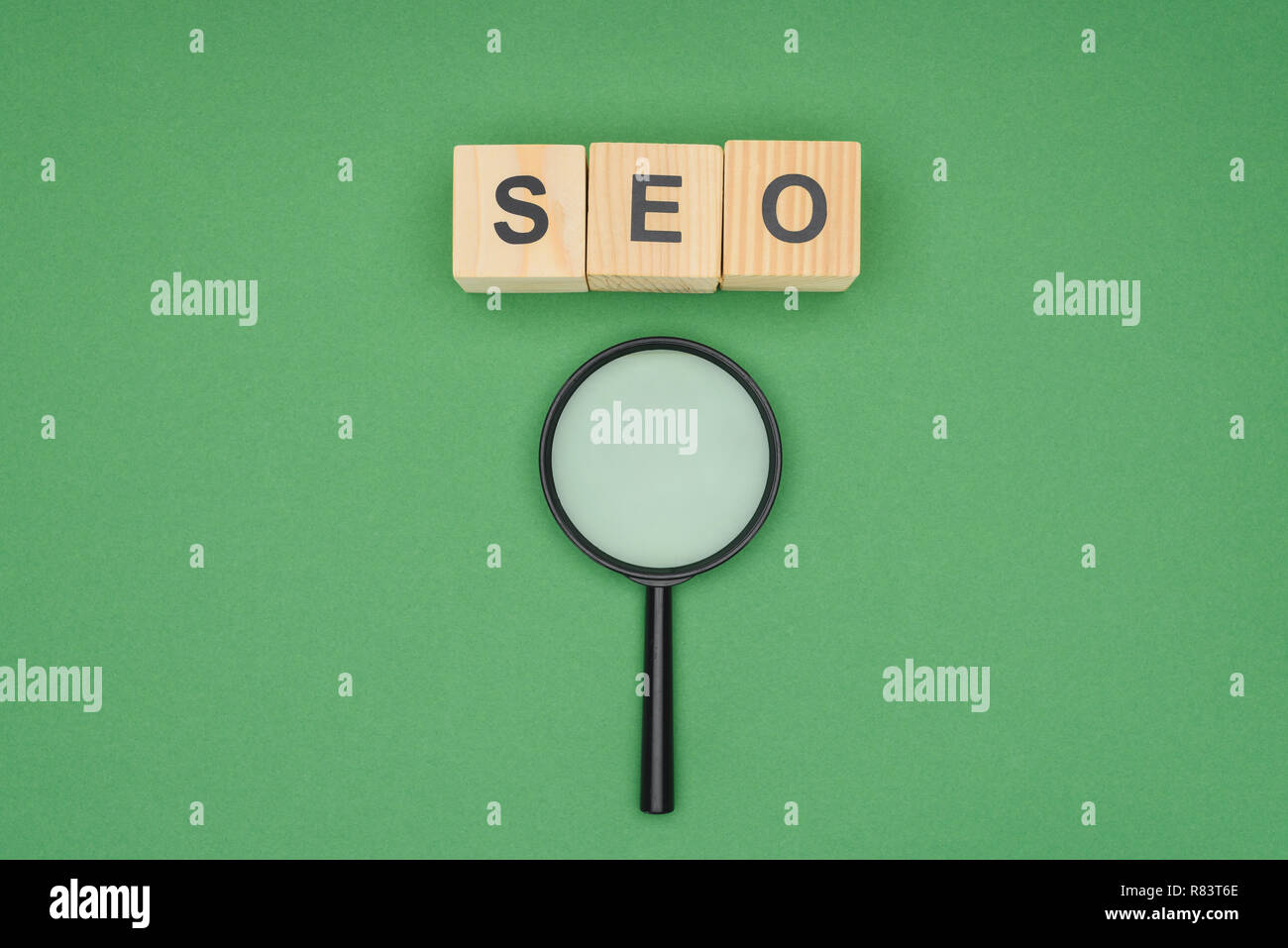 Top view of wooden cubes with letters and magnifier on green background ...