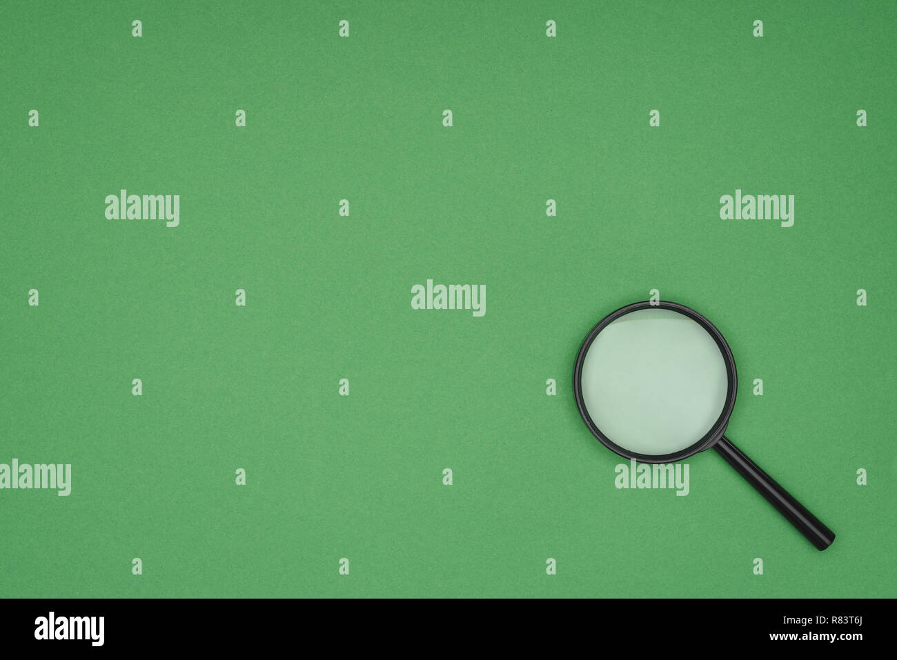 Top view of magnifying glass on green background Stock Photo - Alamy