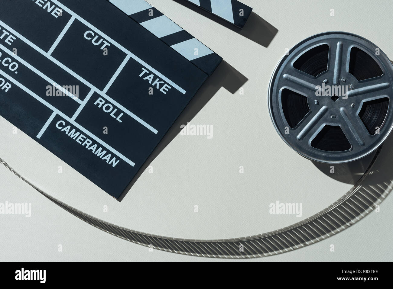 top view of clapperboard and film reel with cinema tape on grey ...