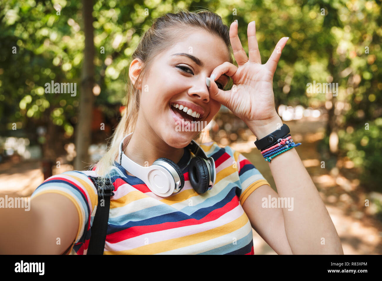 Image of a happy cute young girl take a selfie by camera in park ...
