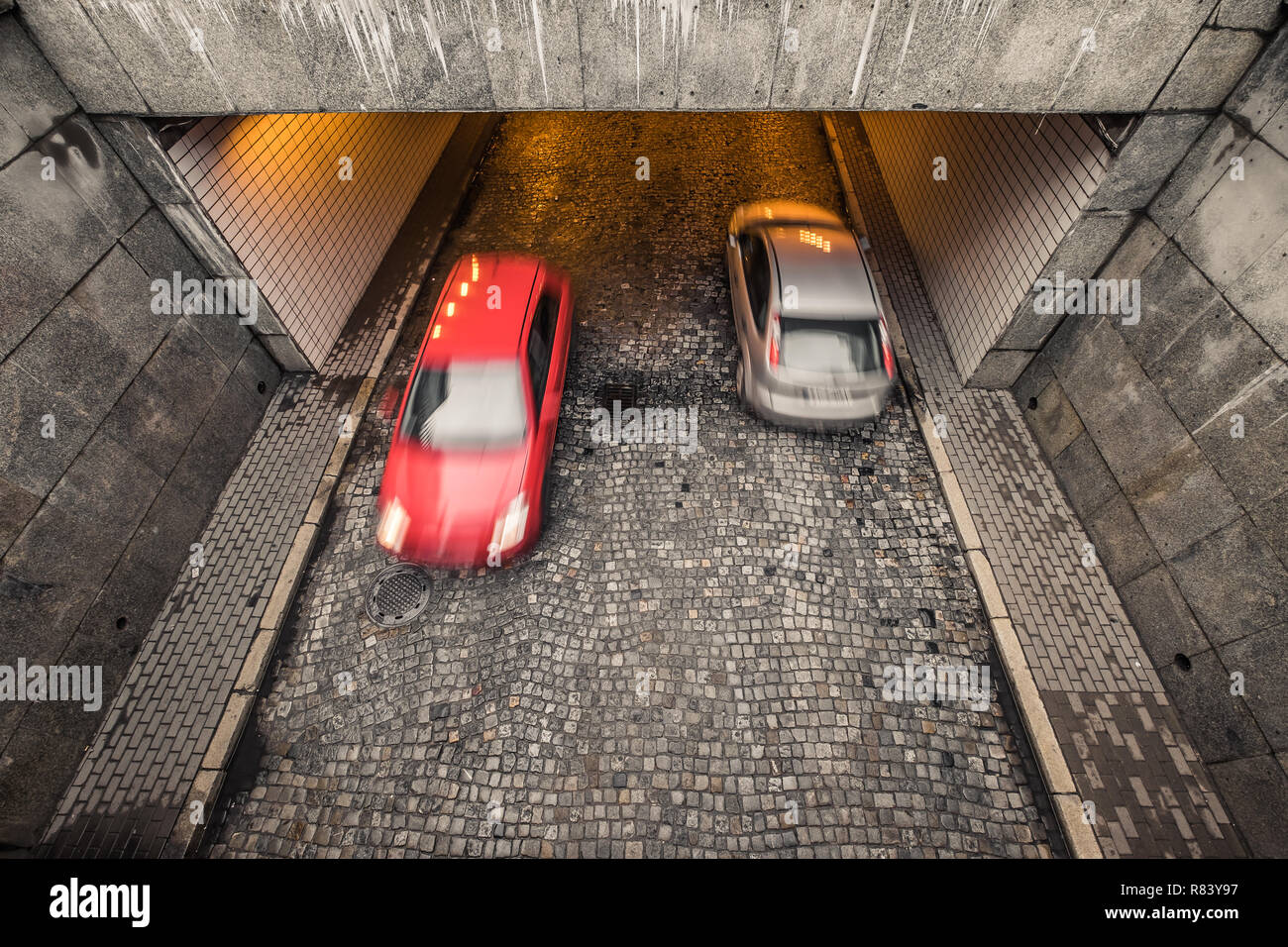 two blurred passanger cars, red and silver, on cobble street in Warsaw ...