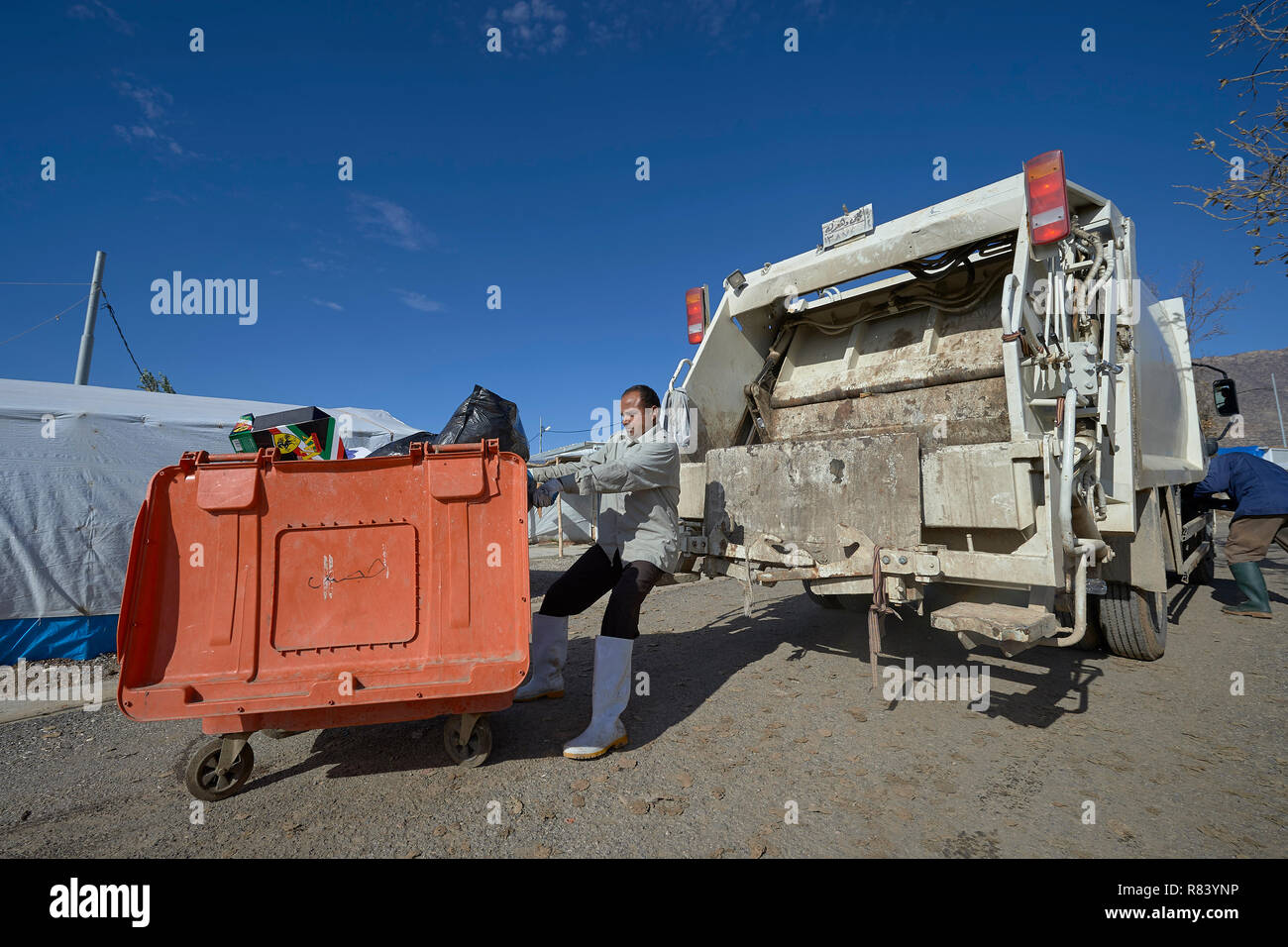 A worker collects garbage in a camp for internally displaced persons at ...