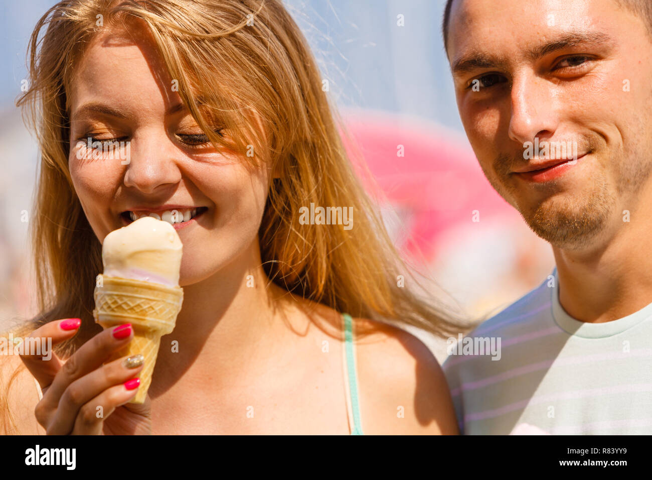 Relationship goals, summer love concept. Man and woman being on date, eating ice cream on beach ...