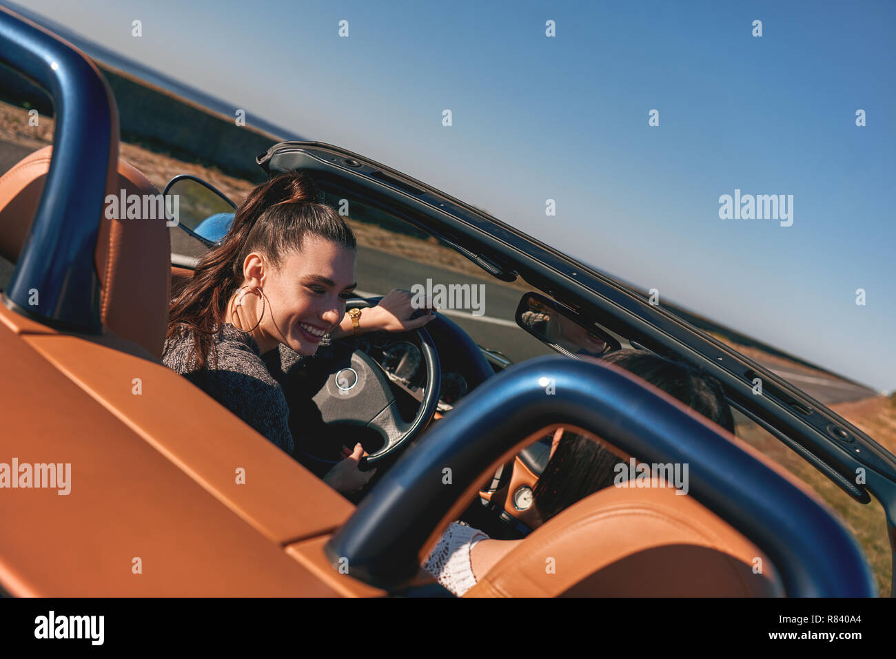 Two happy women in the cabriolet driving and having fun. Rear view ...