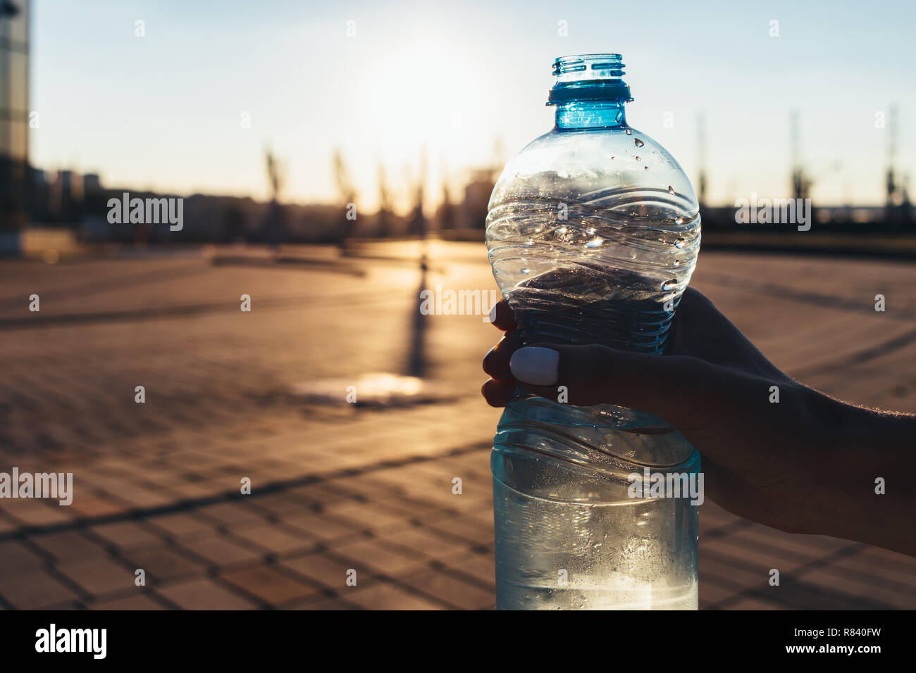 Open bottle of water in woman's hand outdoors in city, close-up Stock ...