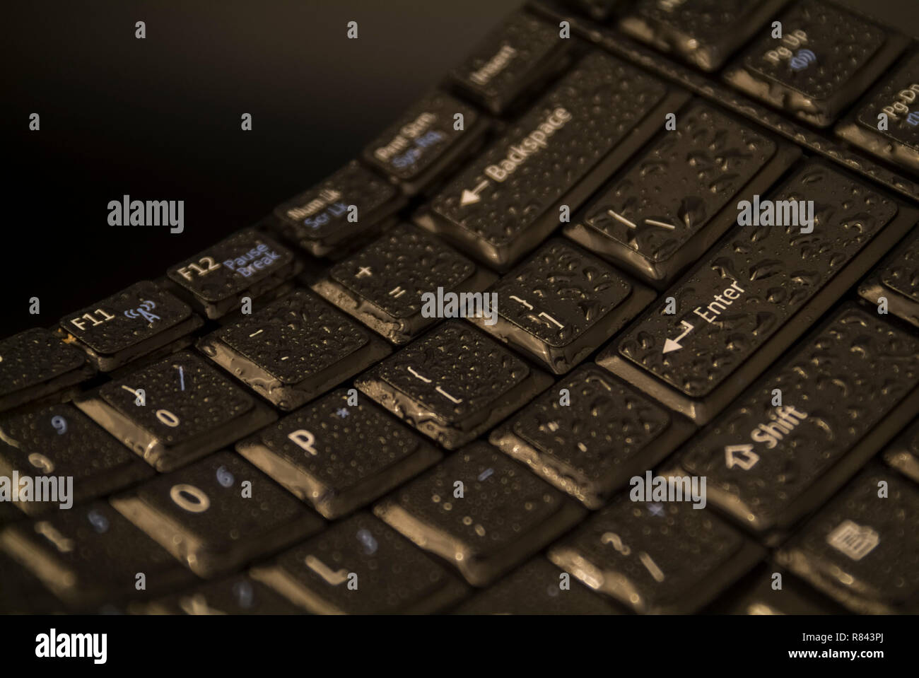 curved black keyboard with a wet surface focusing on the enter key ...