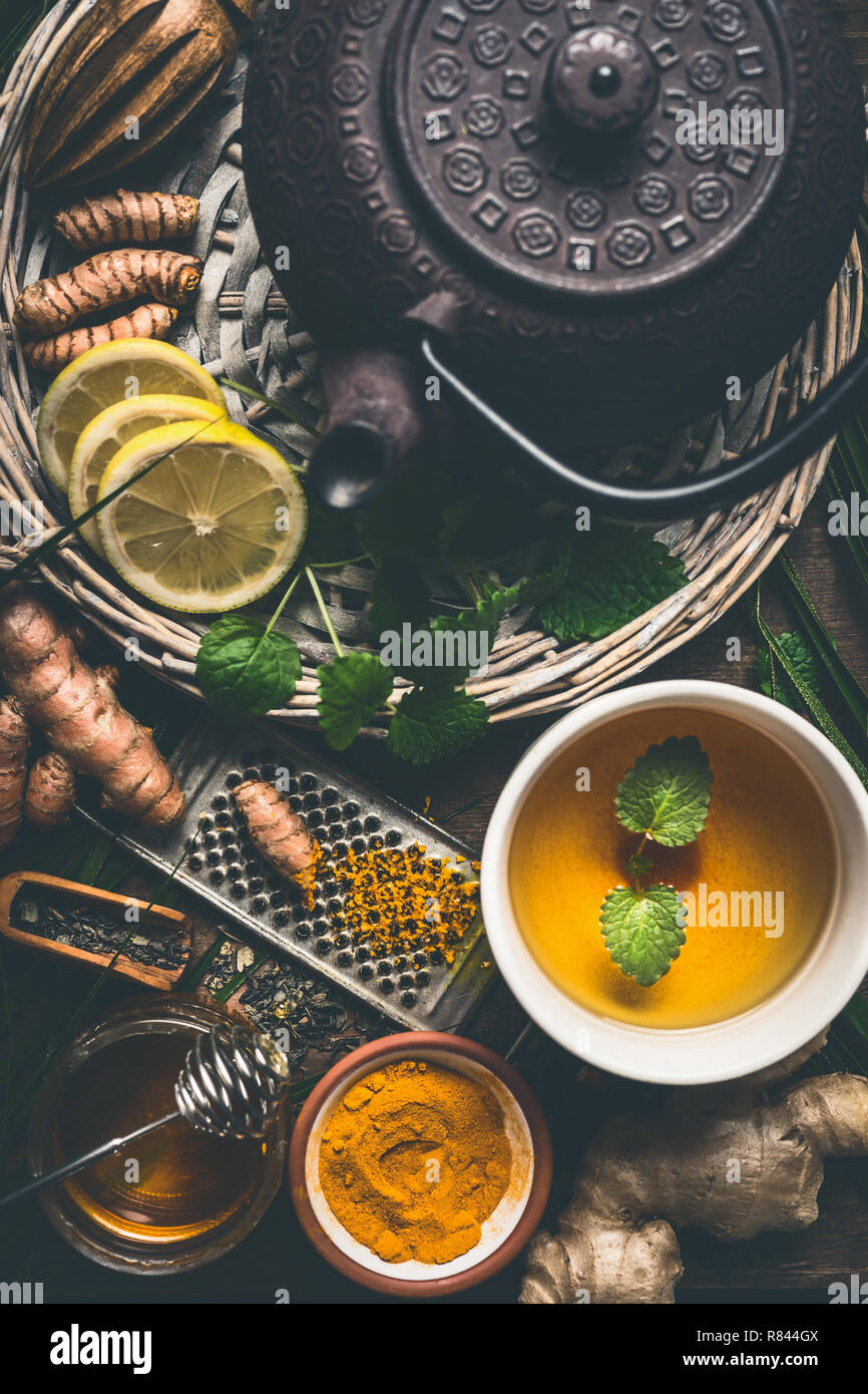 Cup of healthy turmeric spice tea with iron teapot and ingredients ...