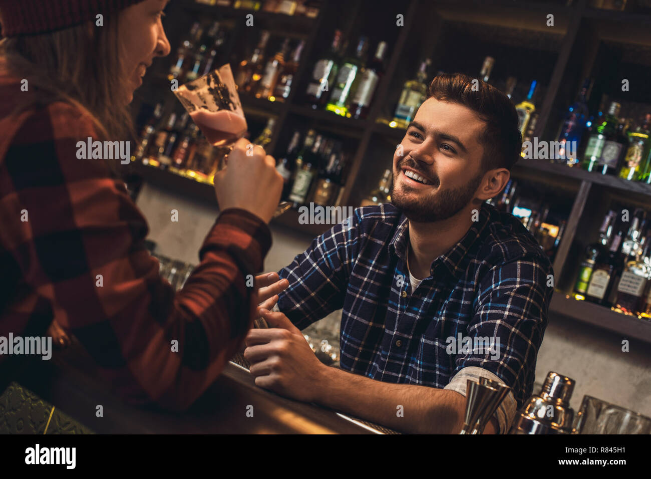 Young bartender leaning on bar counter talking with customer happy Stock Photo - Alamy