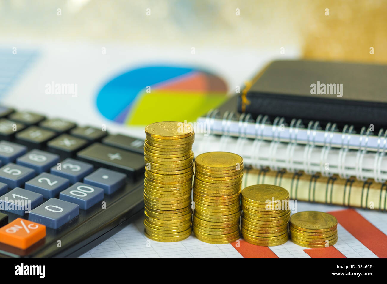 Coin stack and financial graph paper sheet with calculator on working ...